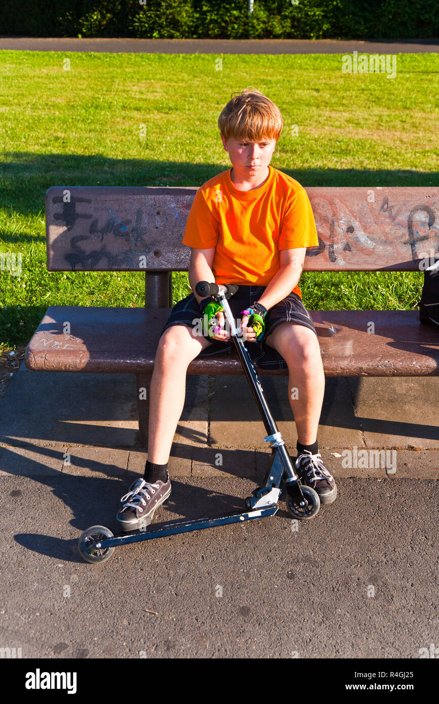 boy sitting on a bench with his scooter Stock Photo - Alamy