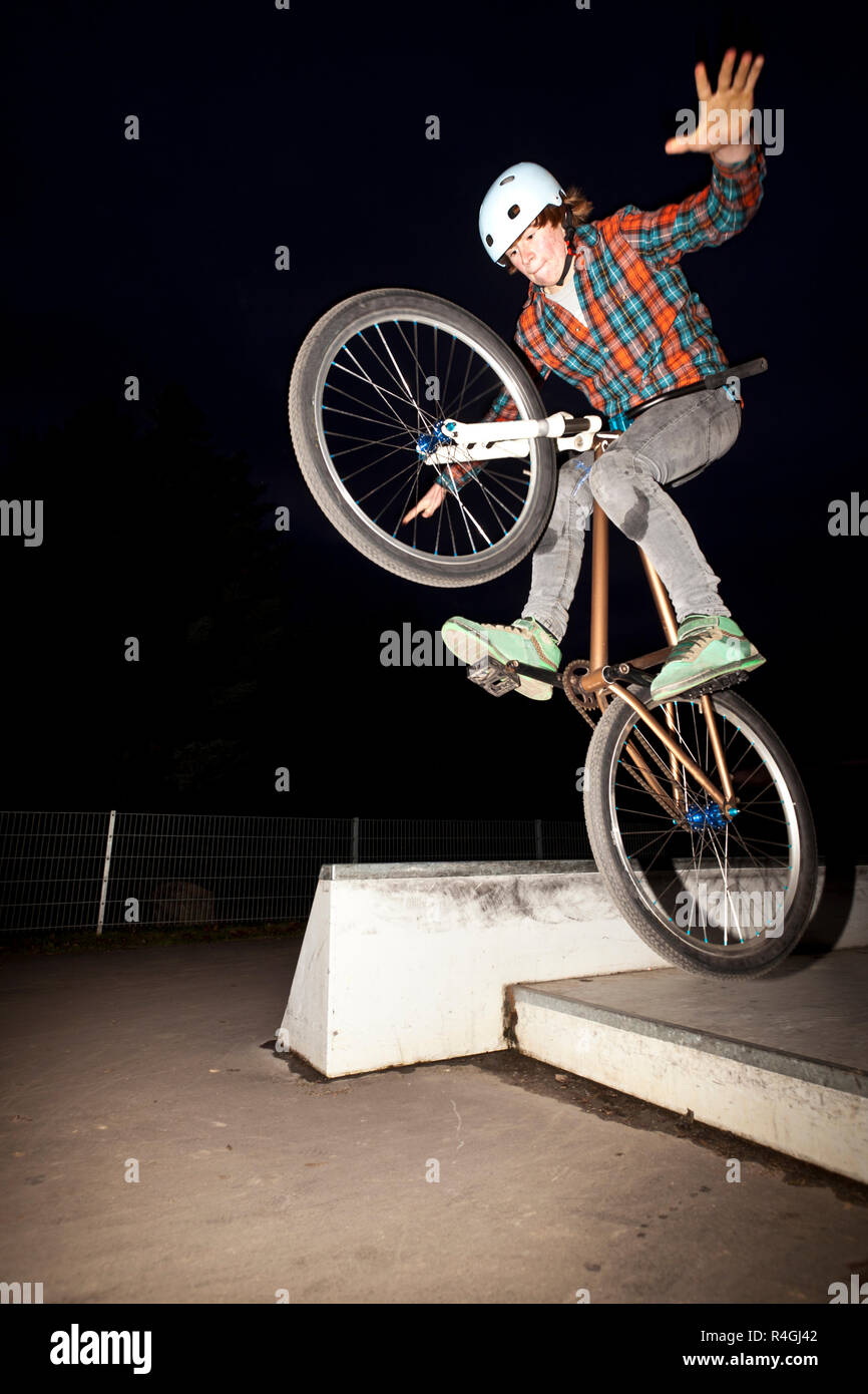 boy jumping with his bike over a ramp by night Stock Photo - Alamy