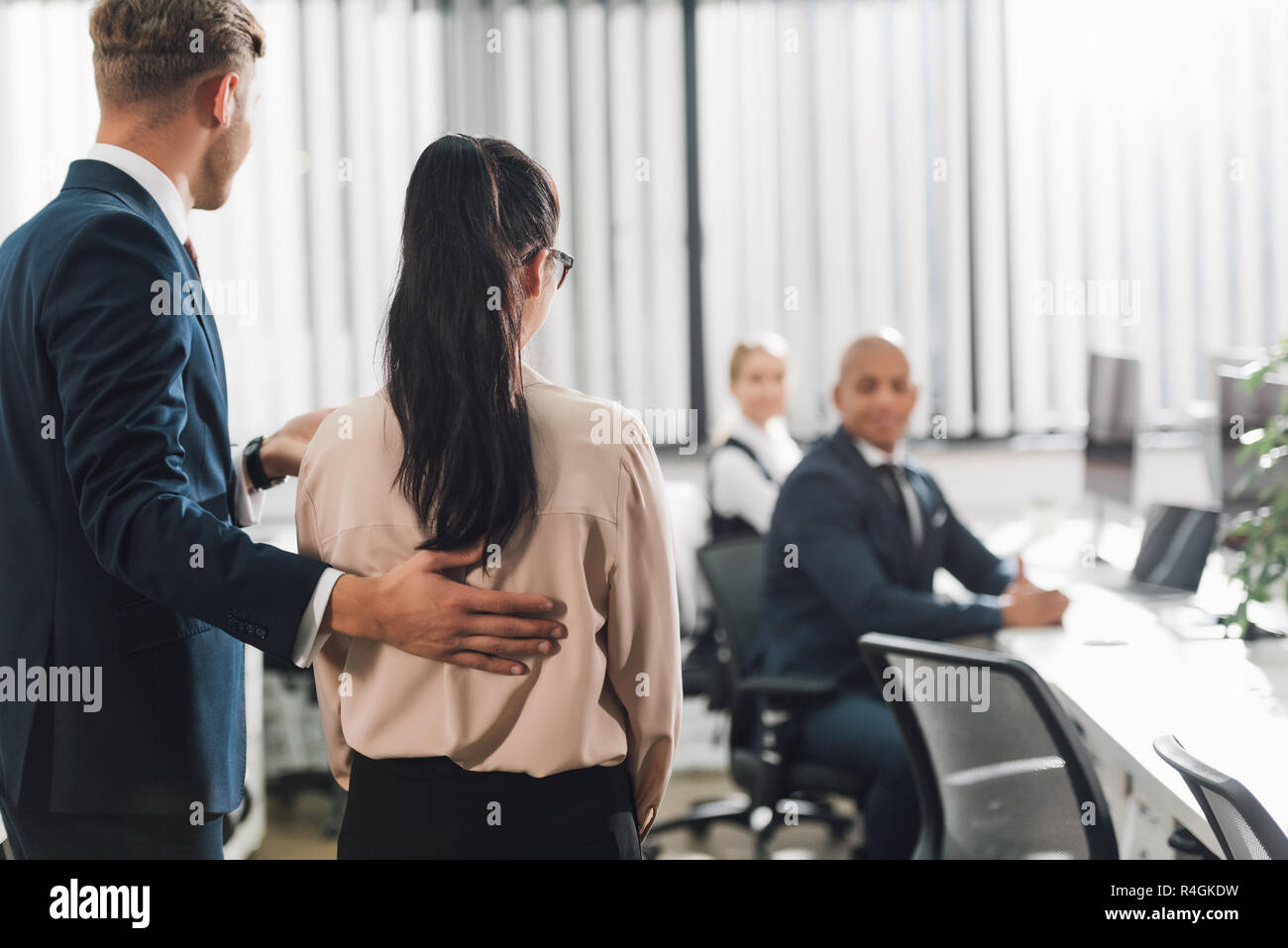 back view of businessman introducing new colleague to young business ...