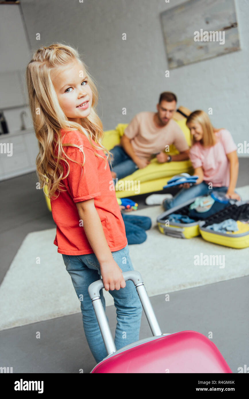 kid holding suitcase while family packing for summer vacation on ...