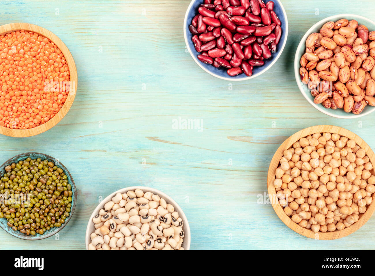 Various types of legumes, shot from the top on a teal background with a ...