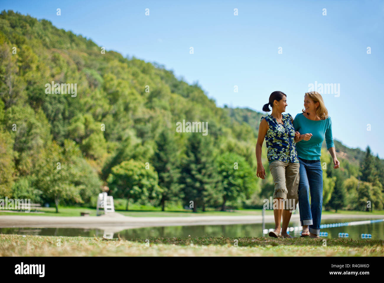 Two smiling friends walking arm in arm in the park Stock Photo - Alamy