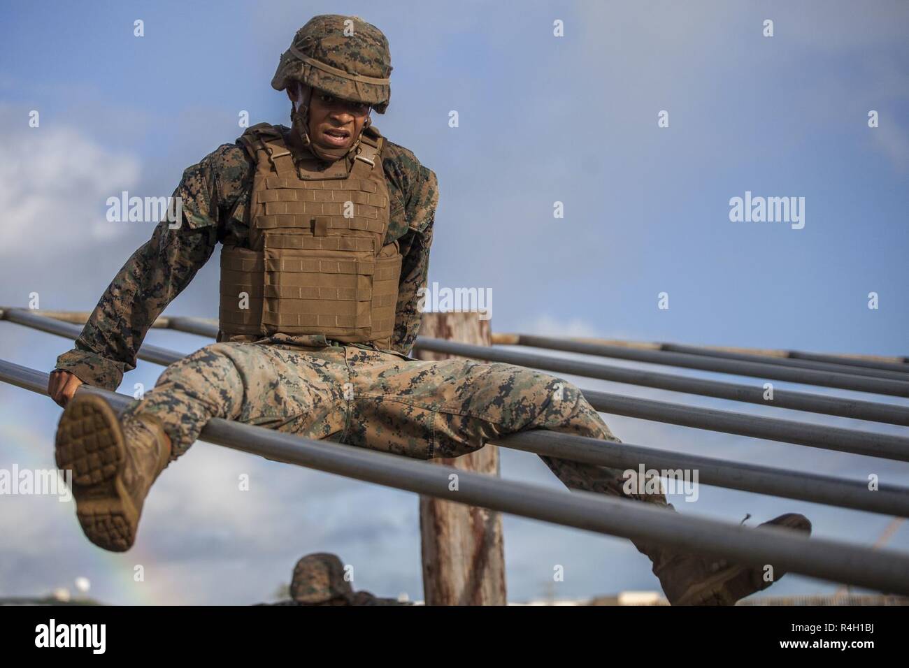A U.S. Marine slides down bars during an obstacle course during a ...