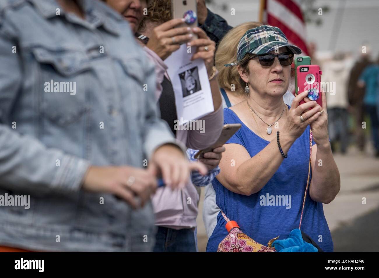 Attendees photograph a procession during a memorial dedication and ...