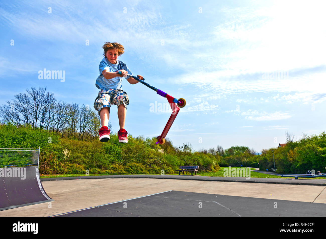 boy is jumping with a scooter over a spine in the skate parc Stock ...