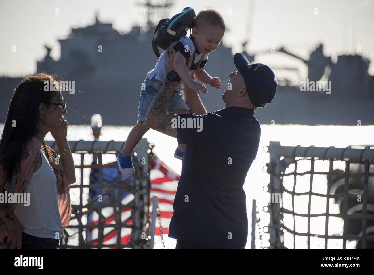 A Coast Guard Cutter Valiant crew member lifts his child with ...