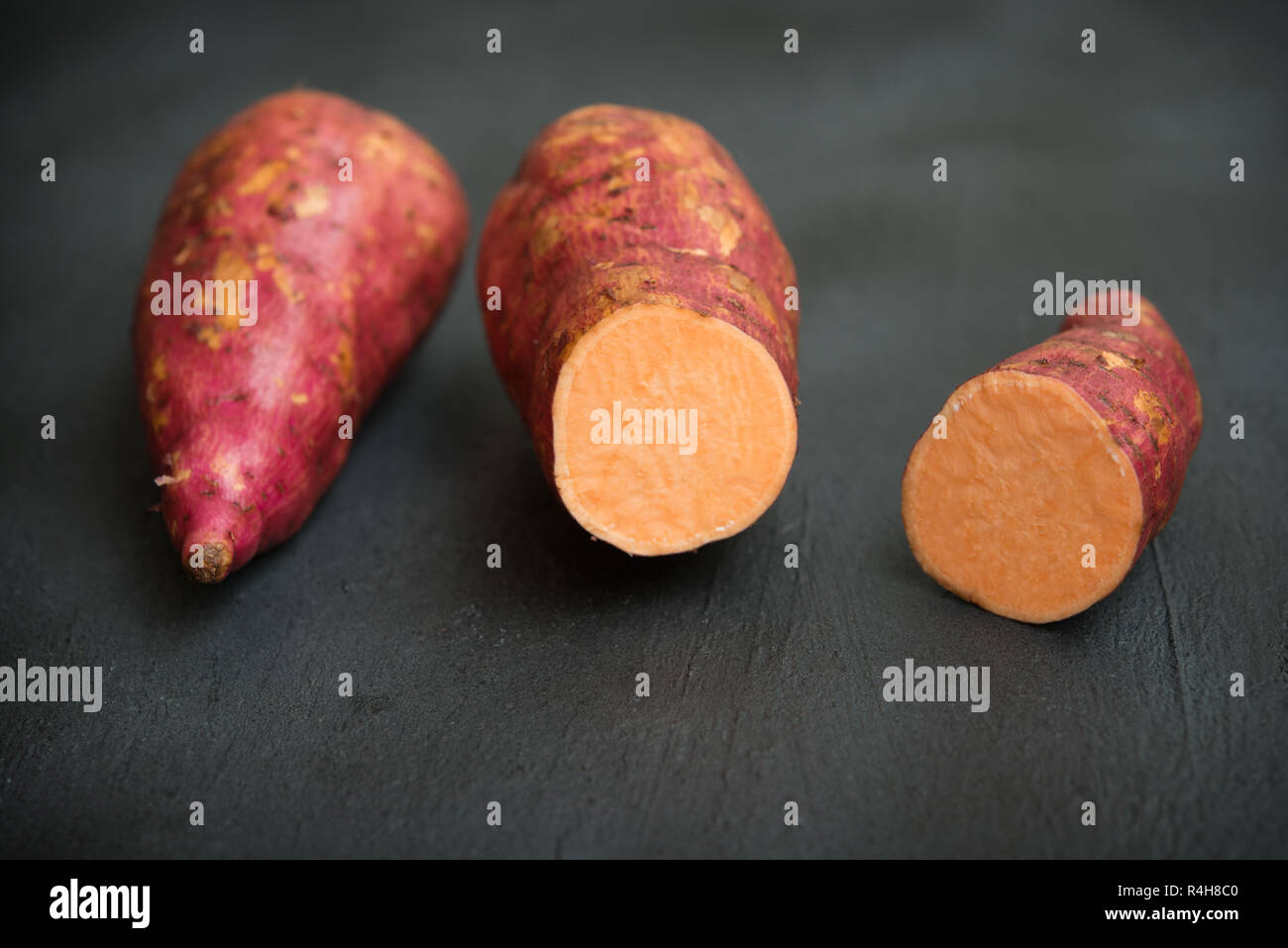 Raw orange sweet potatoes close up on dark background Stock Photo - Alamy