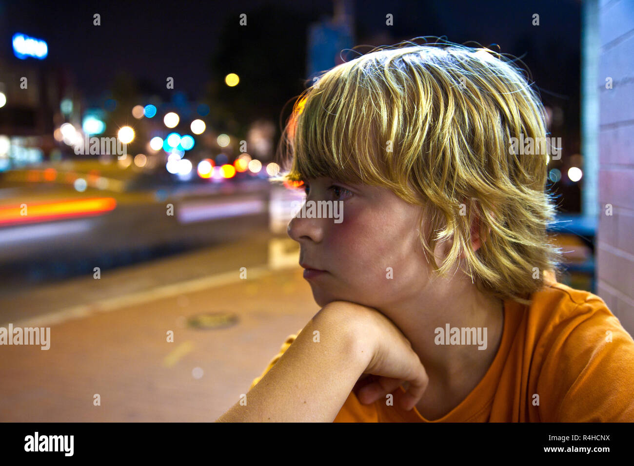 cute boy smiles tired while sitting outside by night Stock Photo - Alamy