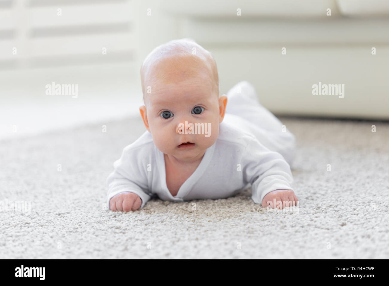 childhood, people concept - baby girl learning to crawl on the floor ...