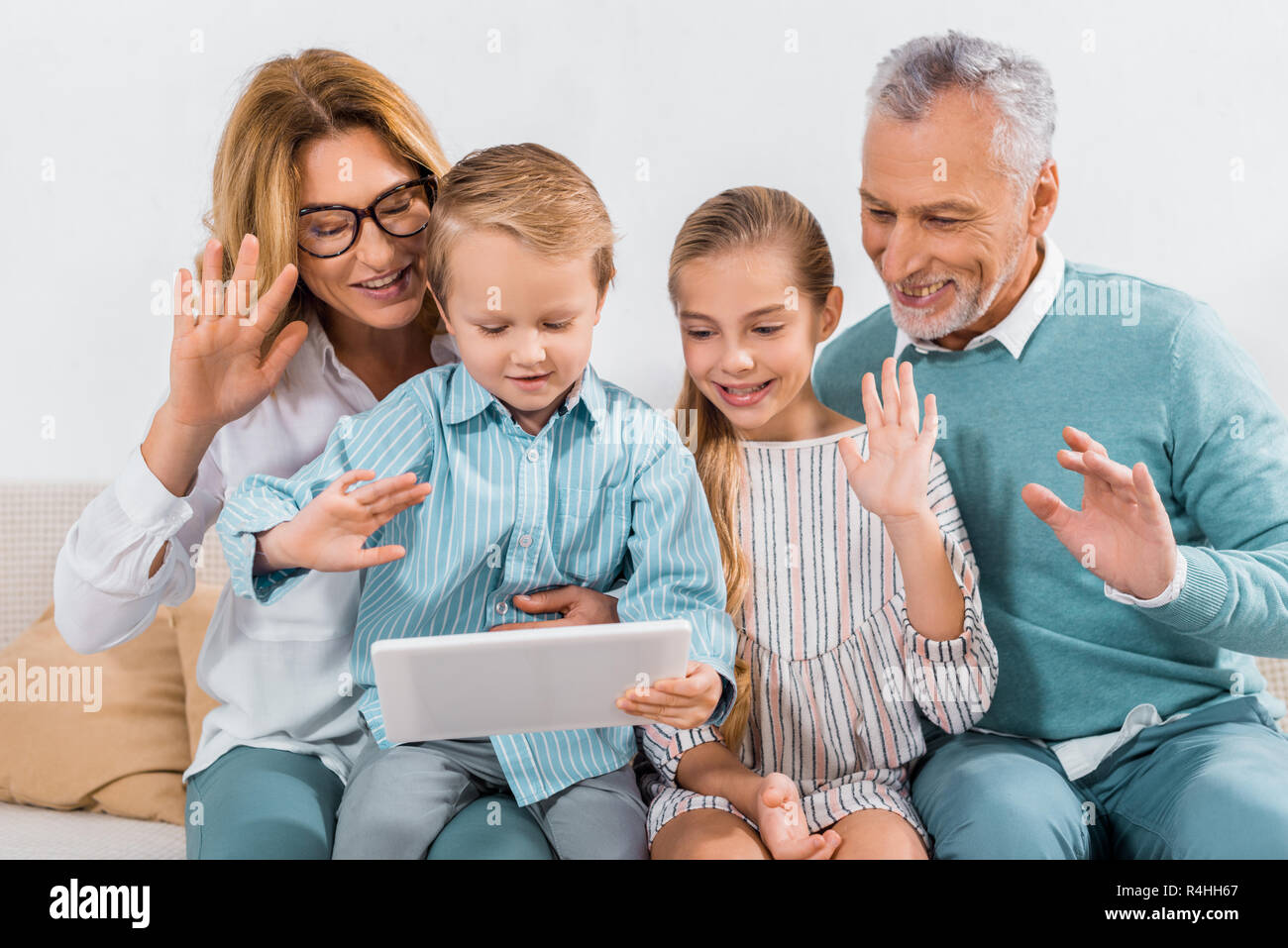 grandparents and grandchildren waving by hands while having video call ...