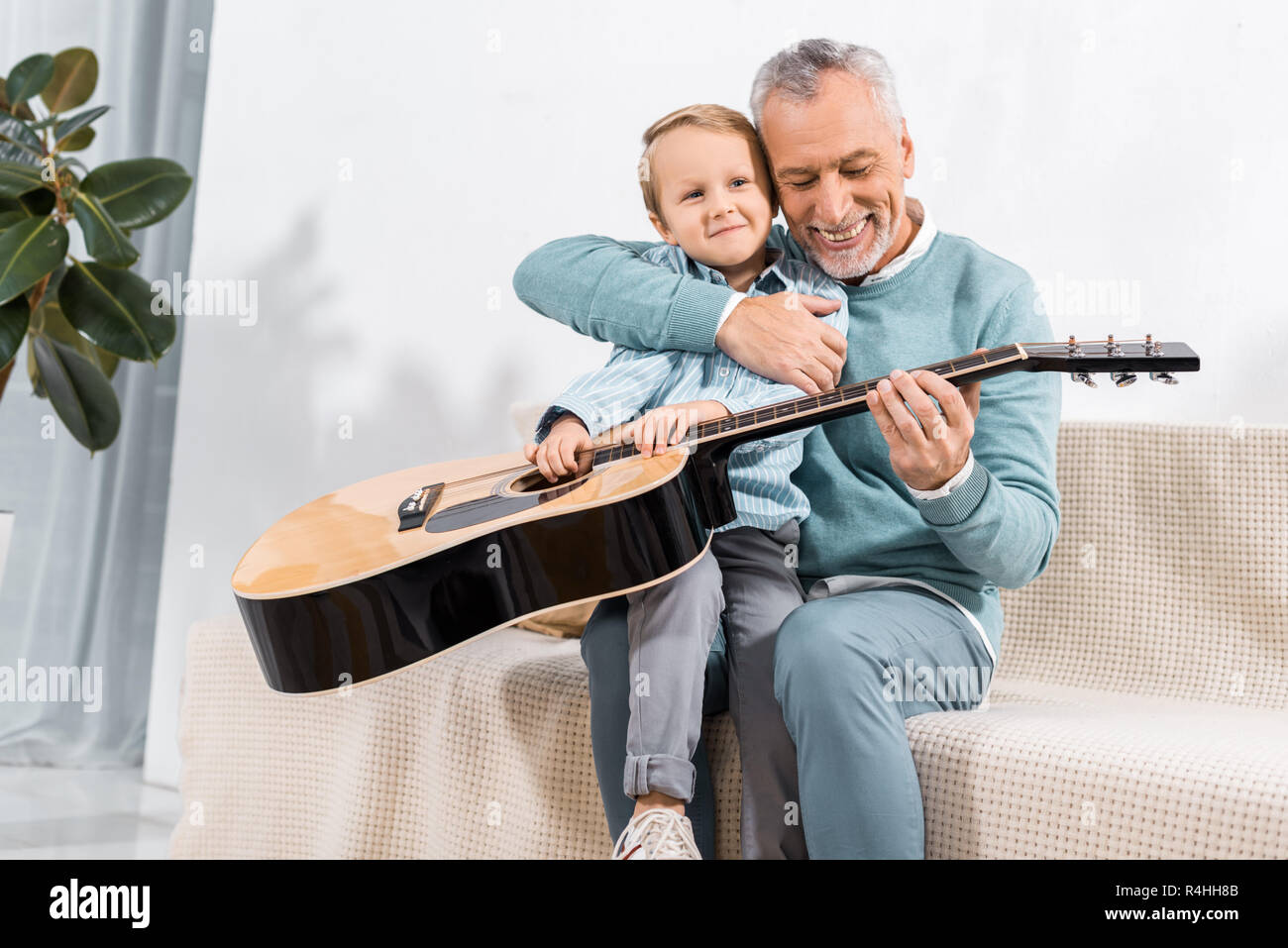 selective focus of laughing grandfather playing with grandson on knees ...