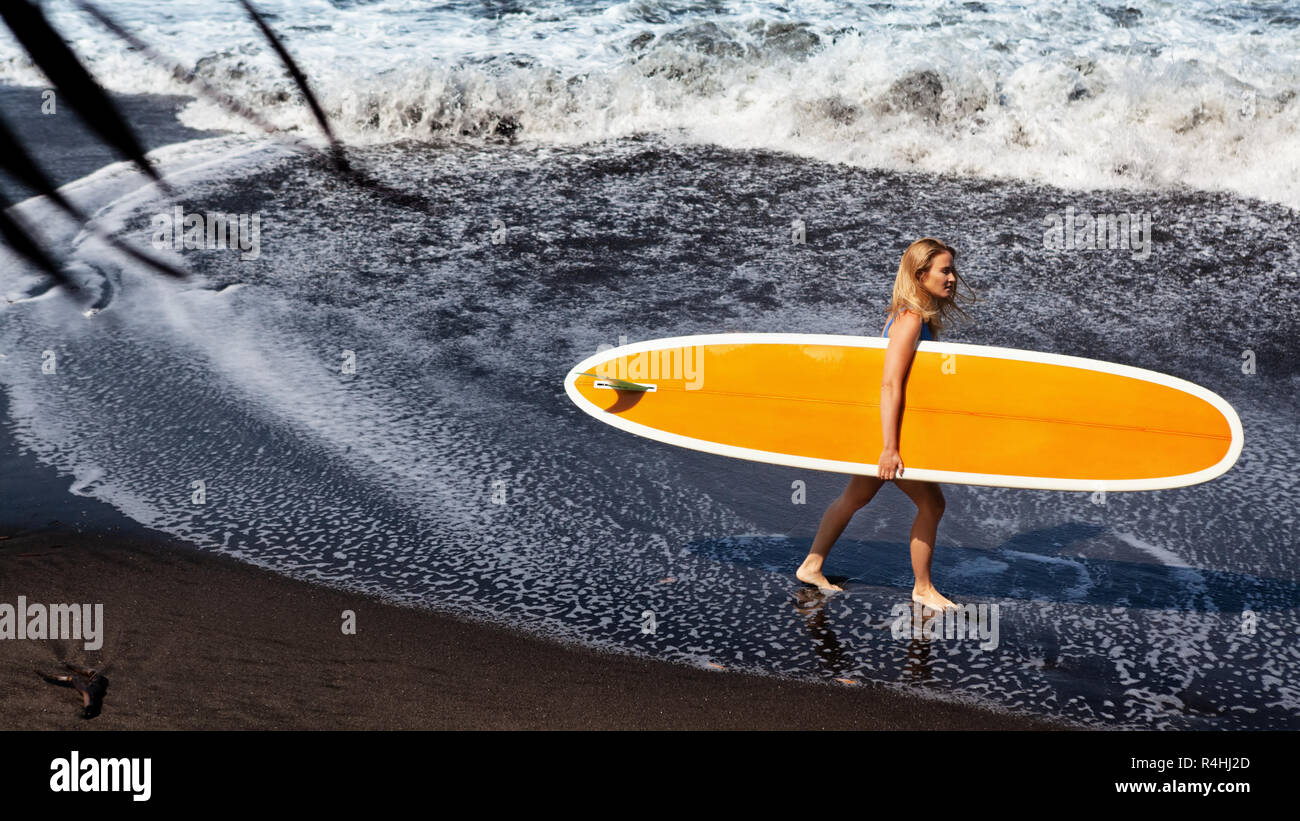Sporty Girl In Bikini With Surf Board Walk On Black Sand Beach Young