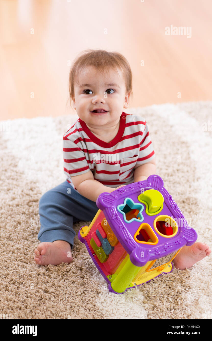 Toddler sitting on carpet and playing with a shape sorter Stock Photo ...