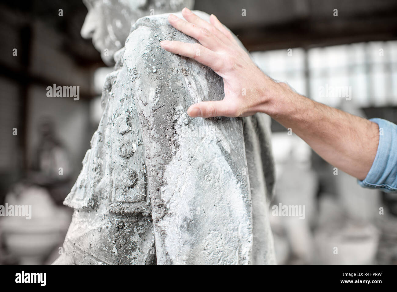 Sculptor touching the old stone sculpture in the studio, close-up view ...