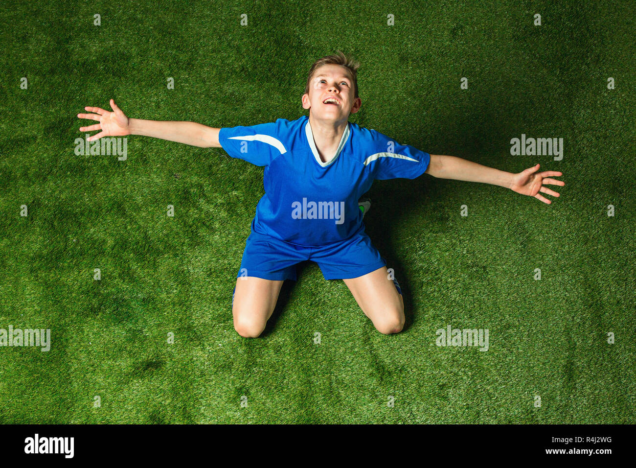 Boy soccer player sitting on green grass Stock Photo - Alamy