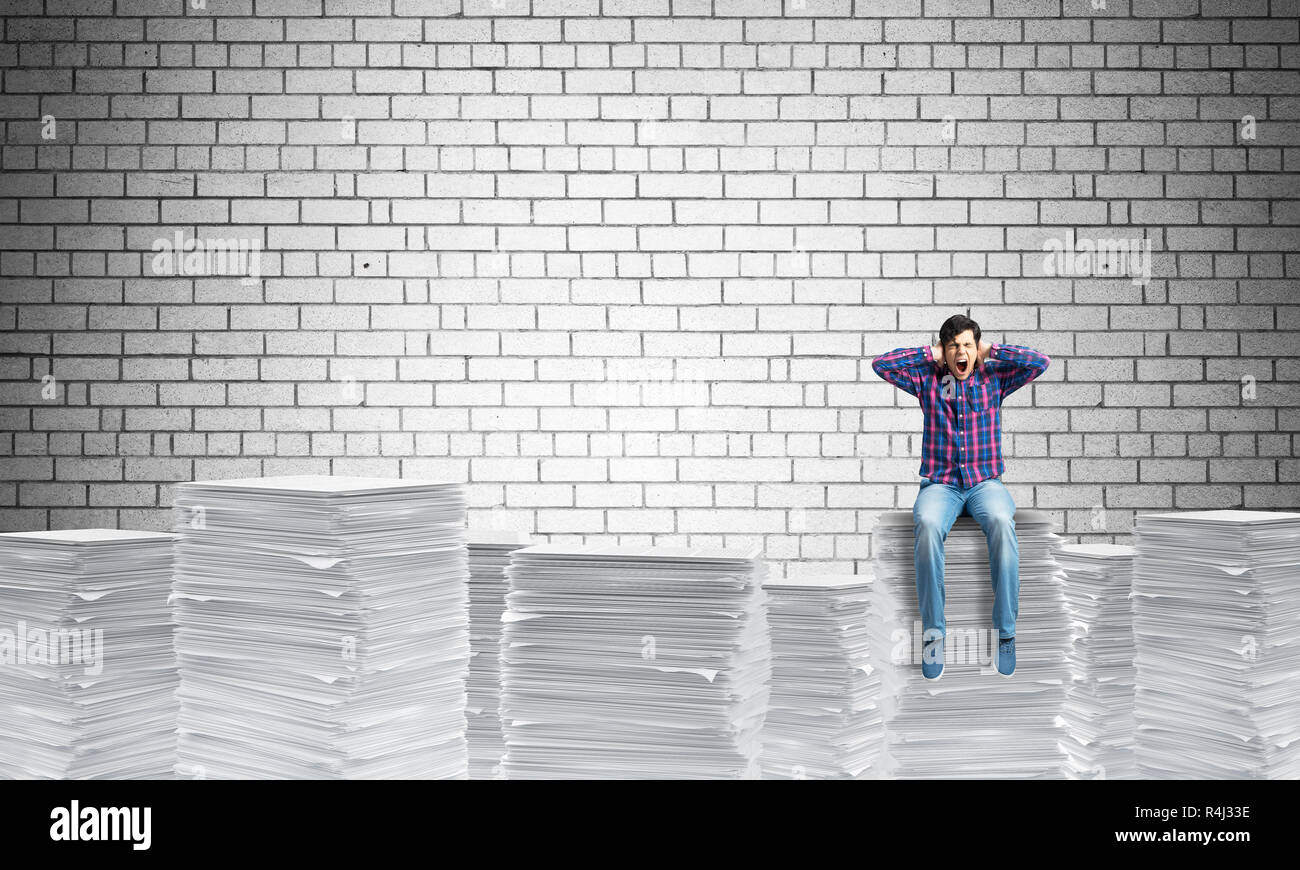 Attractive man sitting on pile of paper documents Stock Photo - Alamy