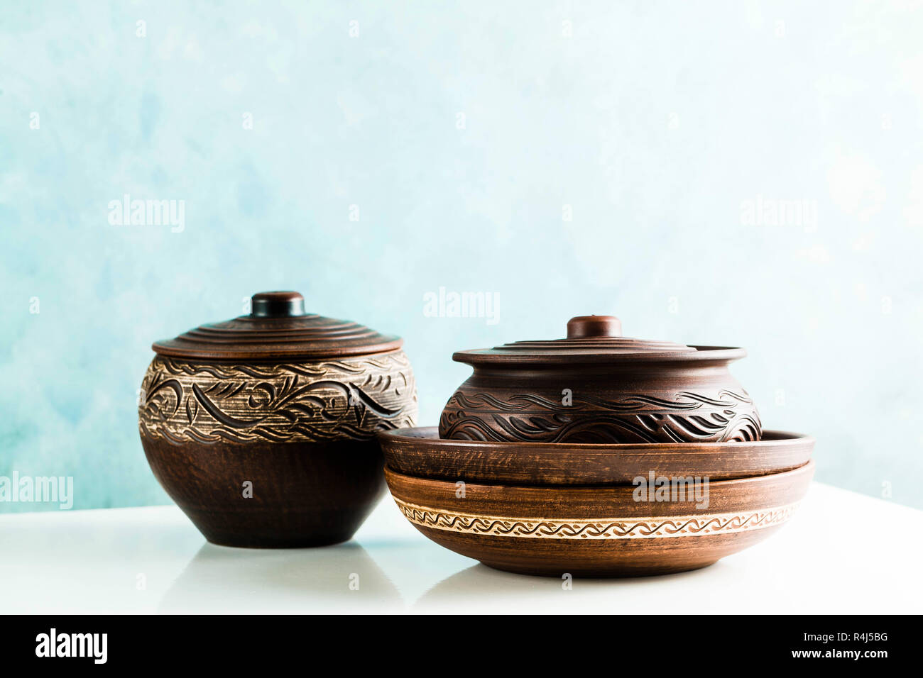 pots and plates of clay on a white table and a blue background. clay ...