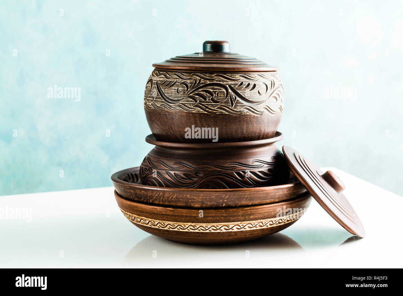 pots and plates of clay on a white table and a blue background. clay ...