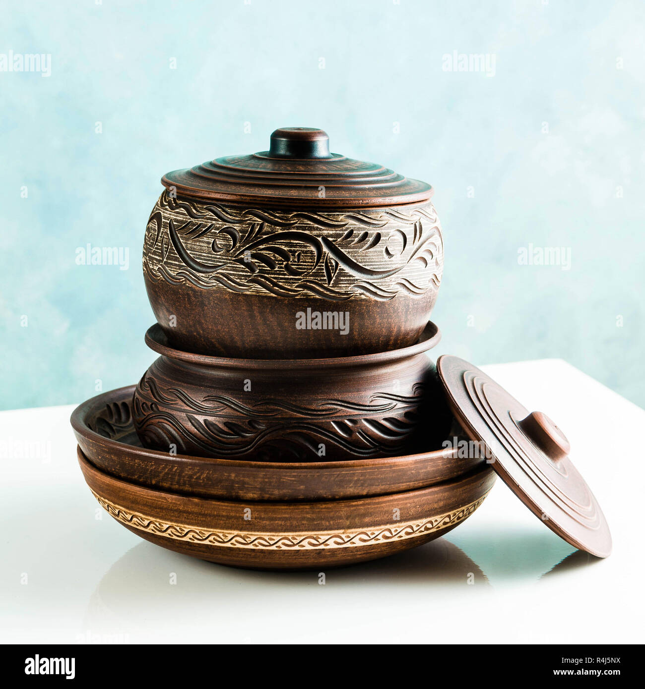 pots and plates of clay on a white table and a blue background. clay ...