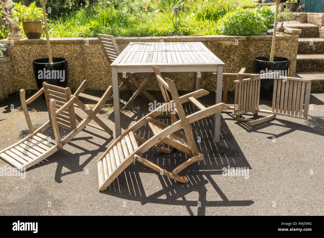 Garden table and chairs pushed over Stock Photo - Alamy