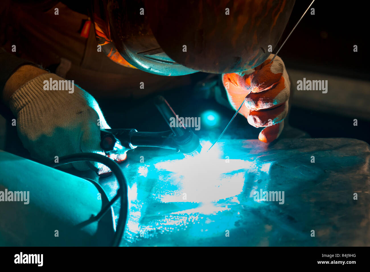 Argon-arc welding welder at the workplace welds the part Stock Photo ...