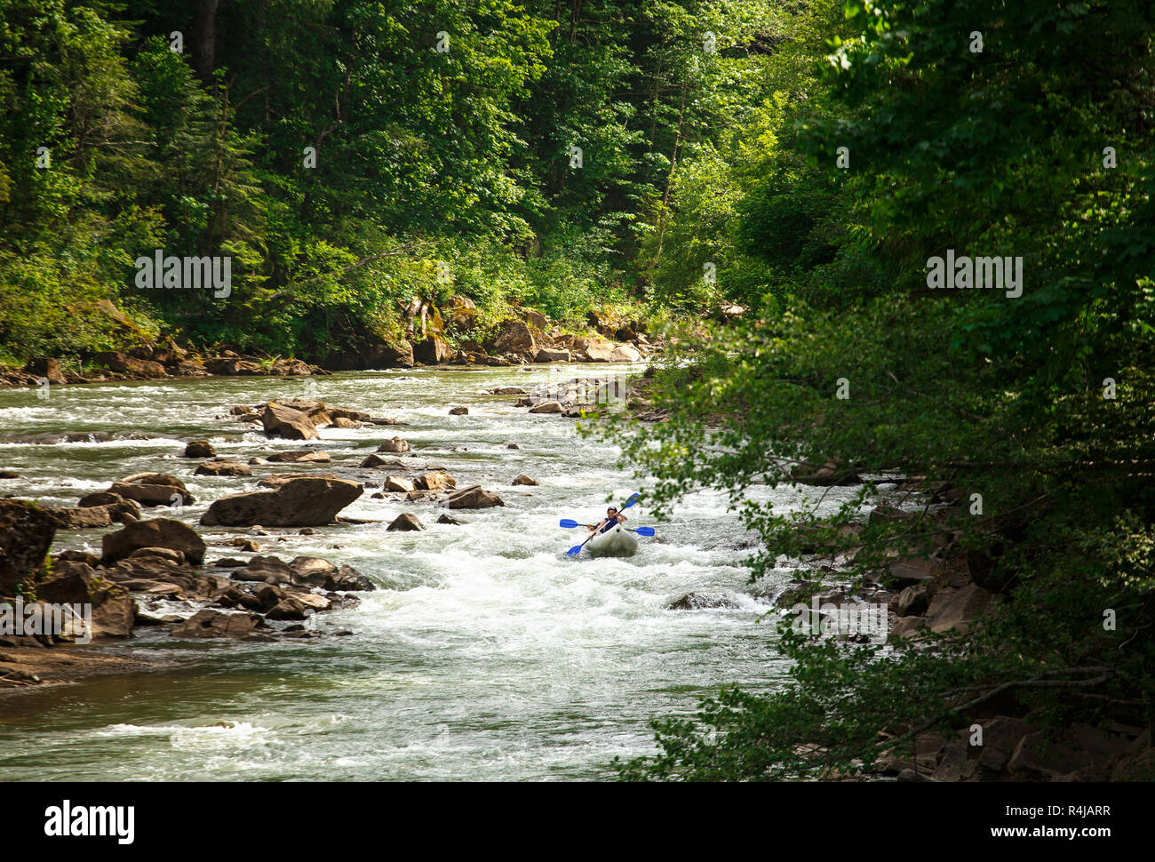 two people floating in a canoe on a mountain river Stock Photo - Alamy