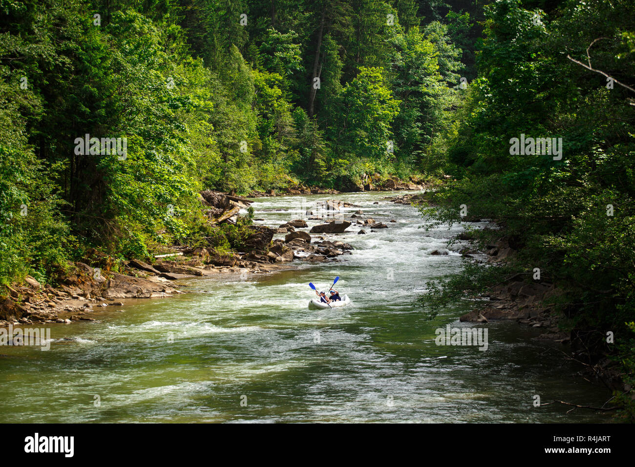 two people floating in a canoe on a mountain river Stock Photo - Alamy