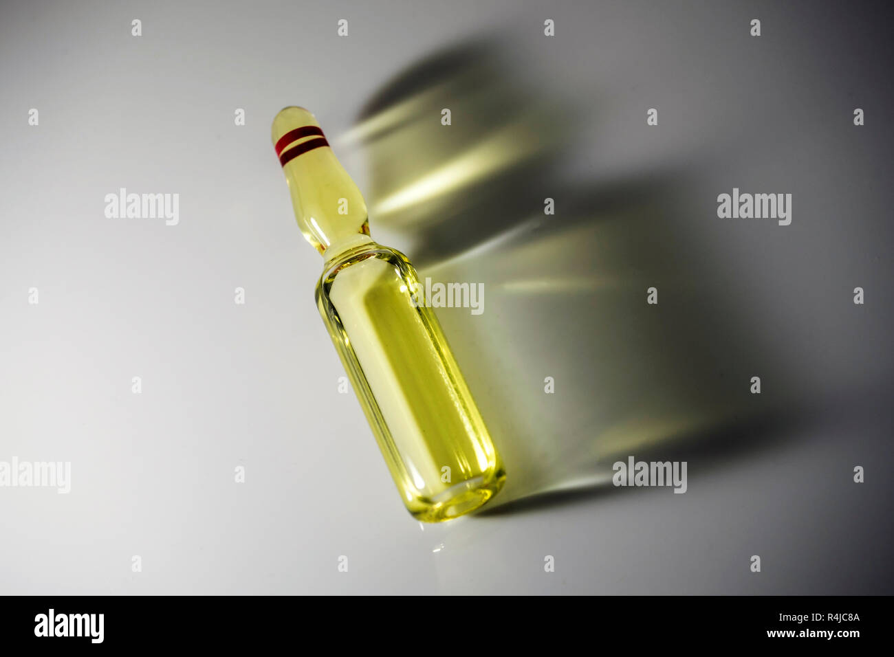 Vial detail with yellow medication, isolated side shadow on white ...