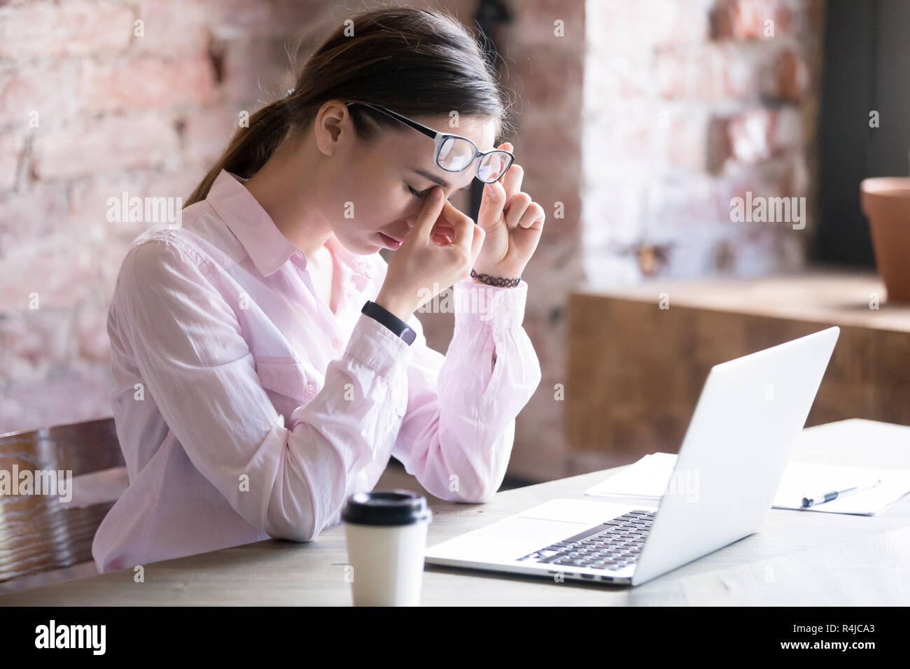 Tired businesswoman holding eyeglasses and massaging nose bridge Stock ...