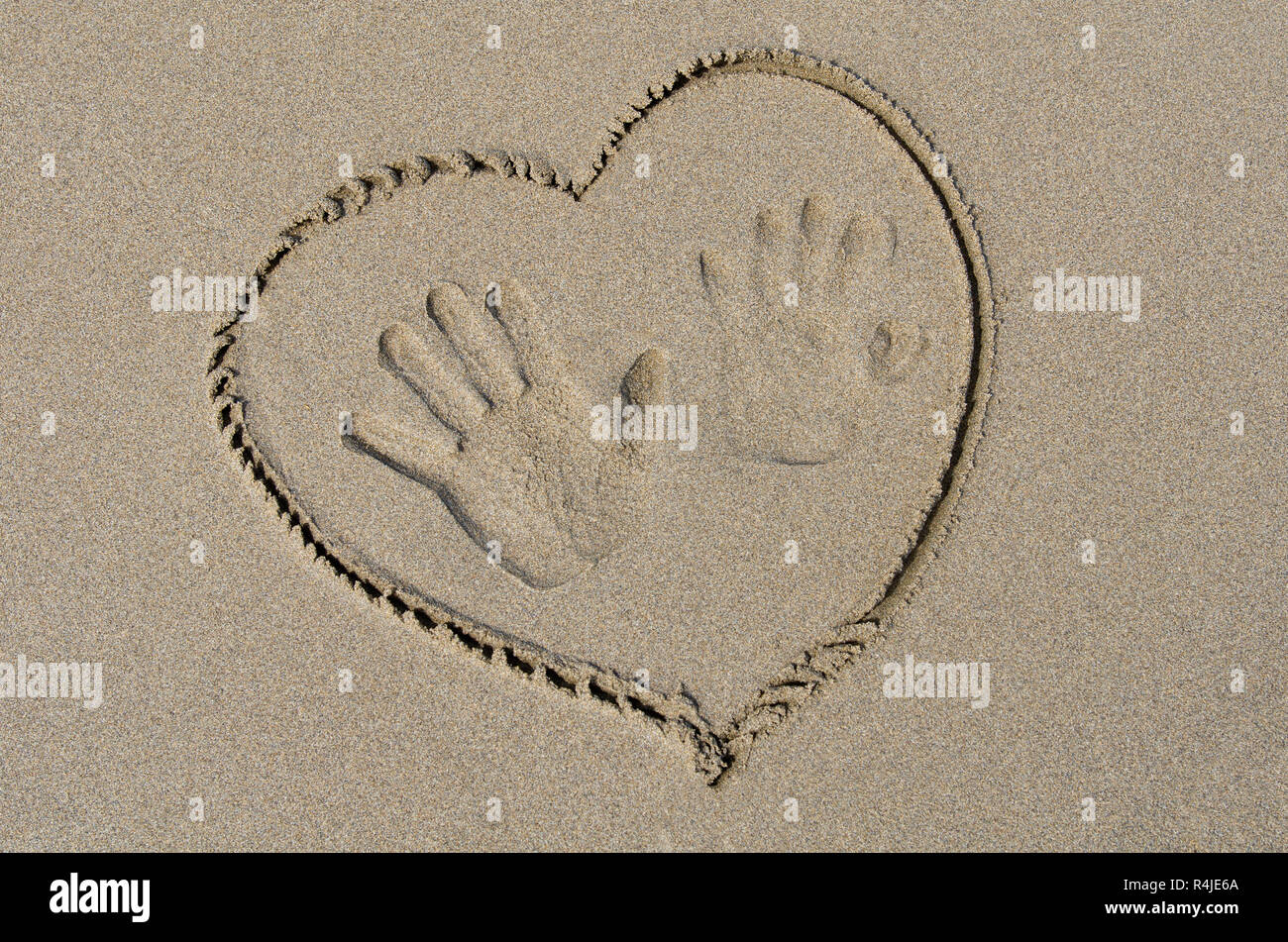 Handprints and heart drawn on the sand Stock Photo - Alamy