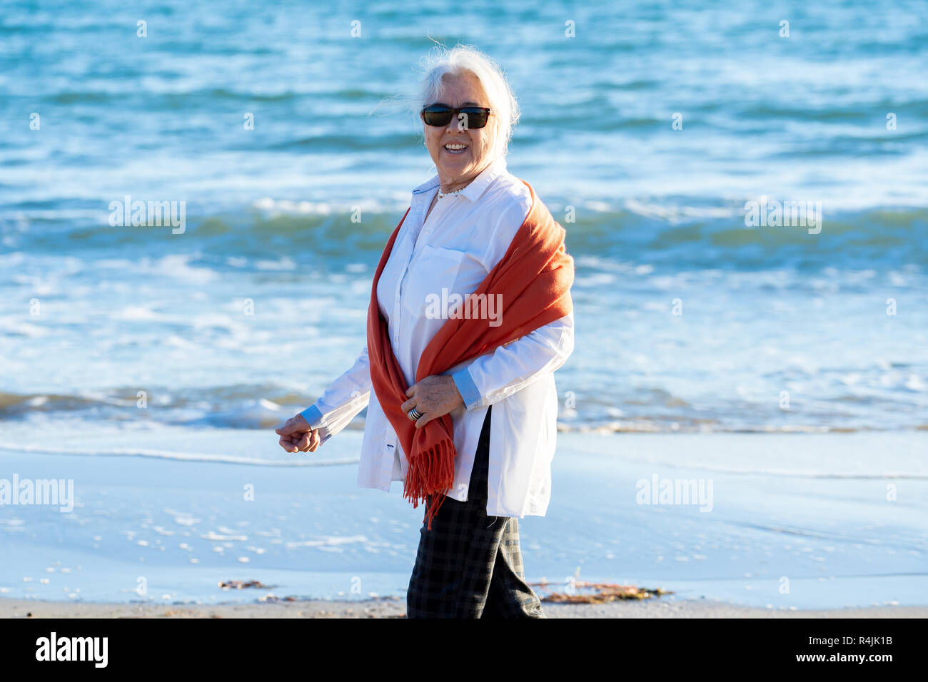 Beautiful retired older woman walking on autumn winter beach on sunset ...
