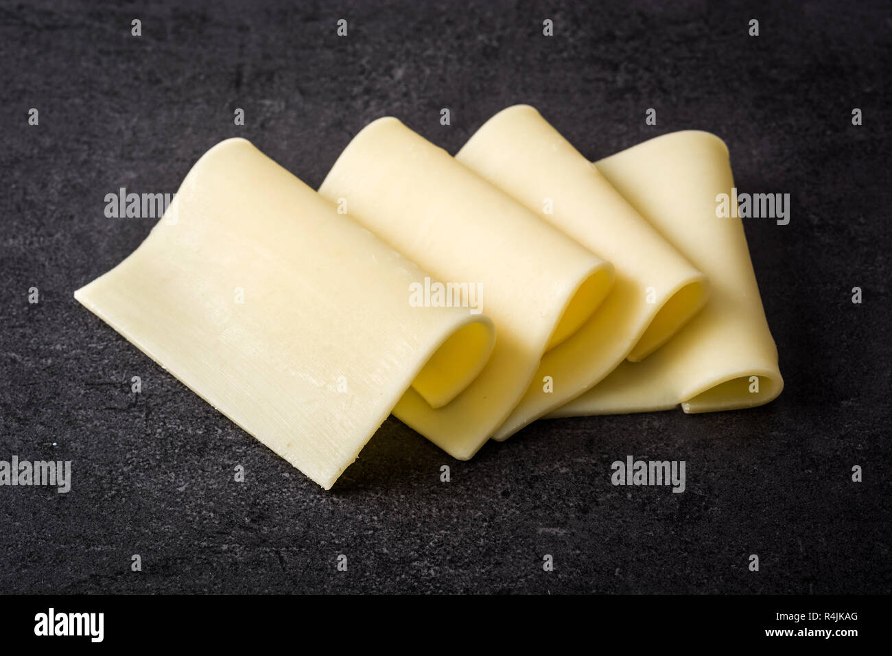 Yellow cheese slices on black slate Stock Photo - Alamy