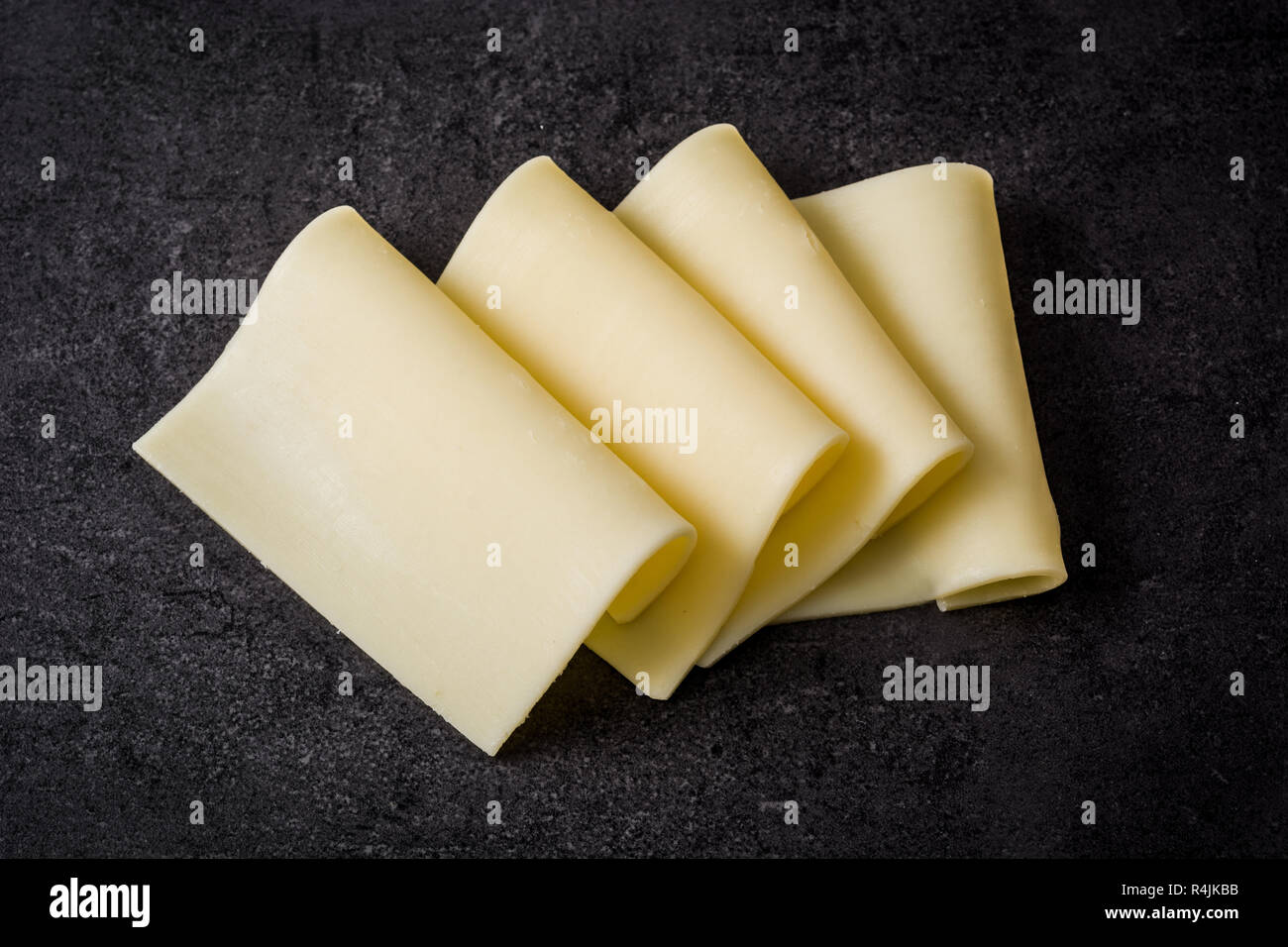 Yellow cheese slices on black slate Stock Photo - Alamy