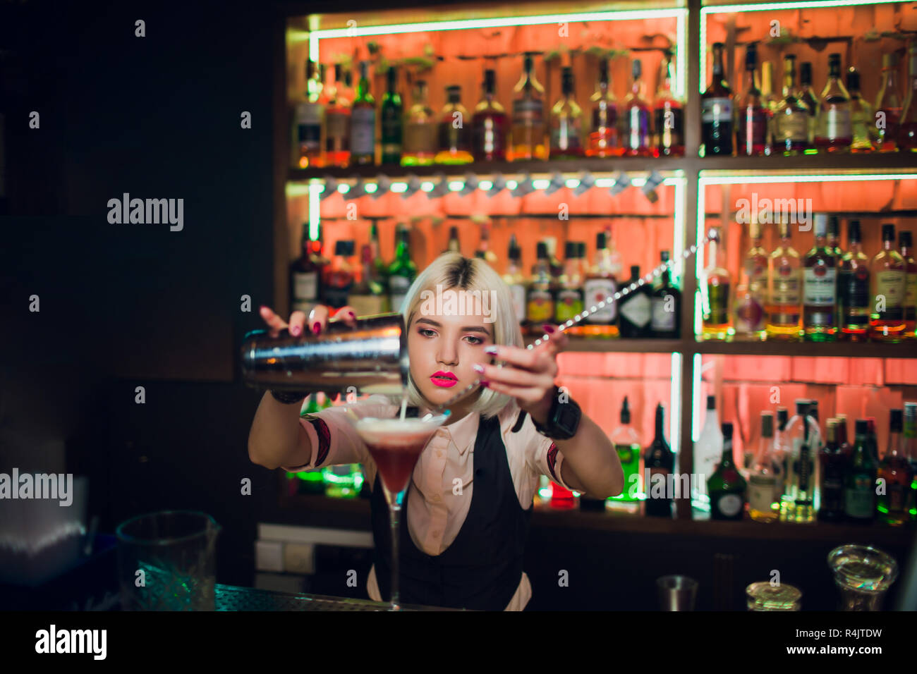 female bartender. girl with blonde hair. cocktail making in night bar ...