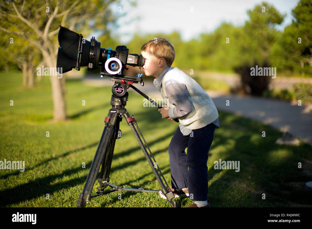 Young boy looking through professional camera Stock Photo - Alamy