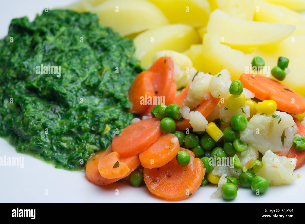 Close-up of Carrots with spinach, peas, cauliflower and potatoes on a ...