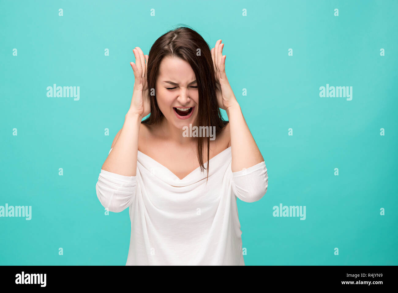 Frustrated young woman posing on blue Stock Photo - Alamy