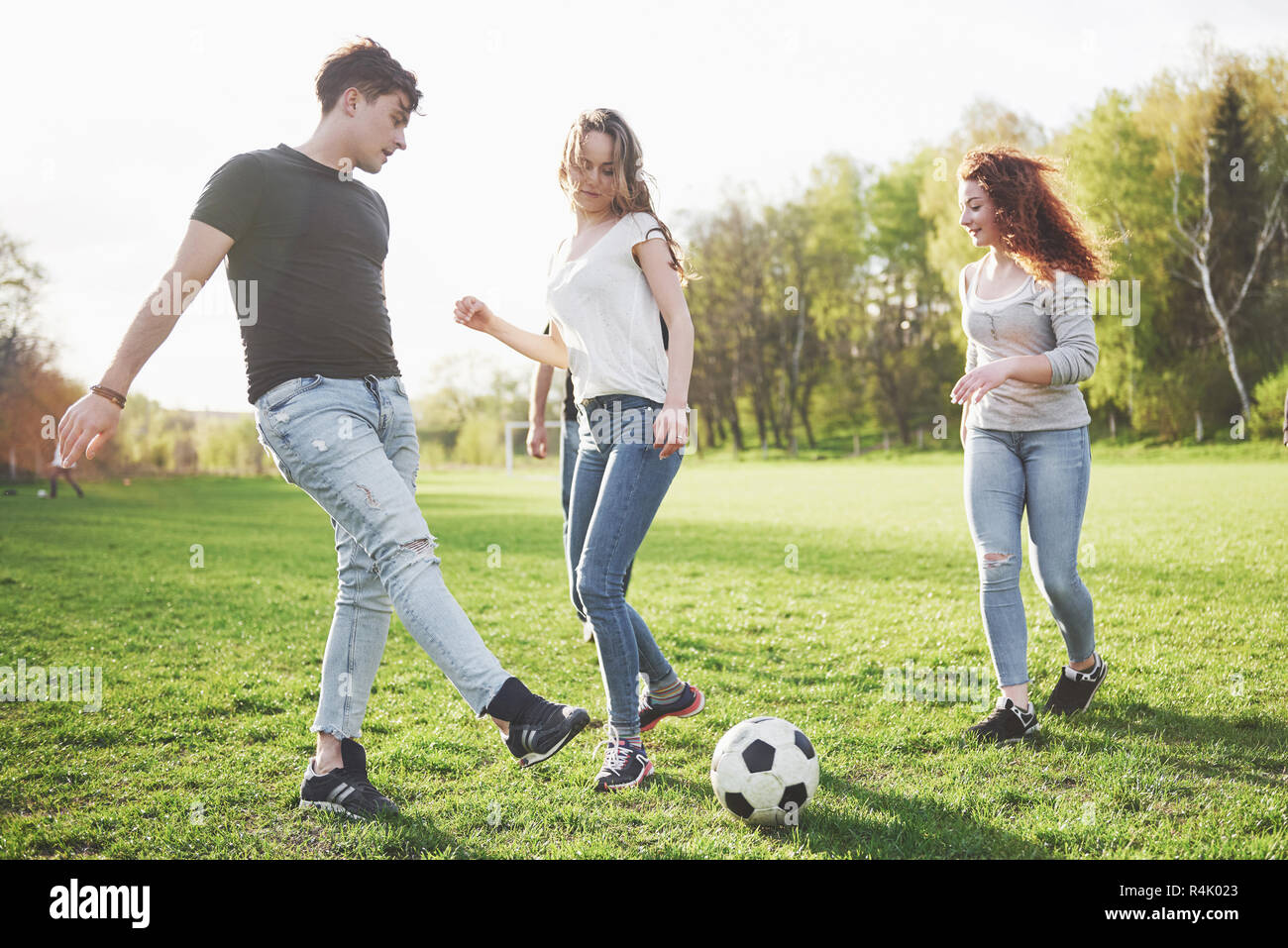 A group of friends in casual outfit play soccer in the open air. People ...