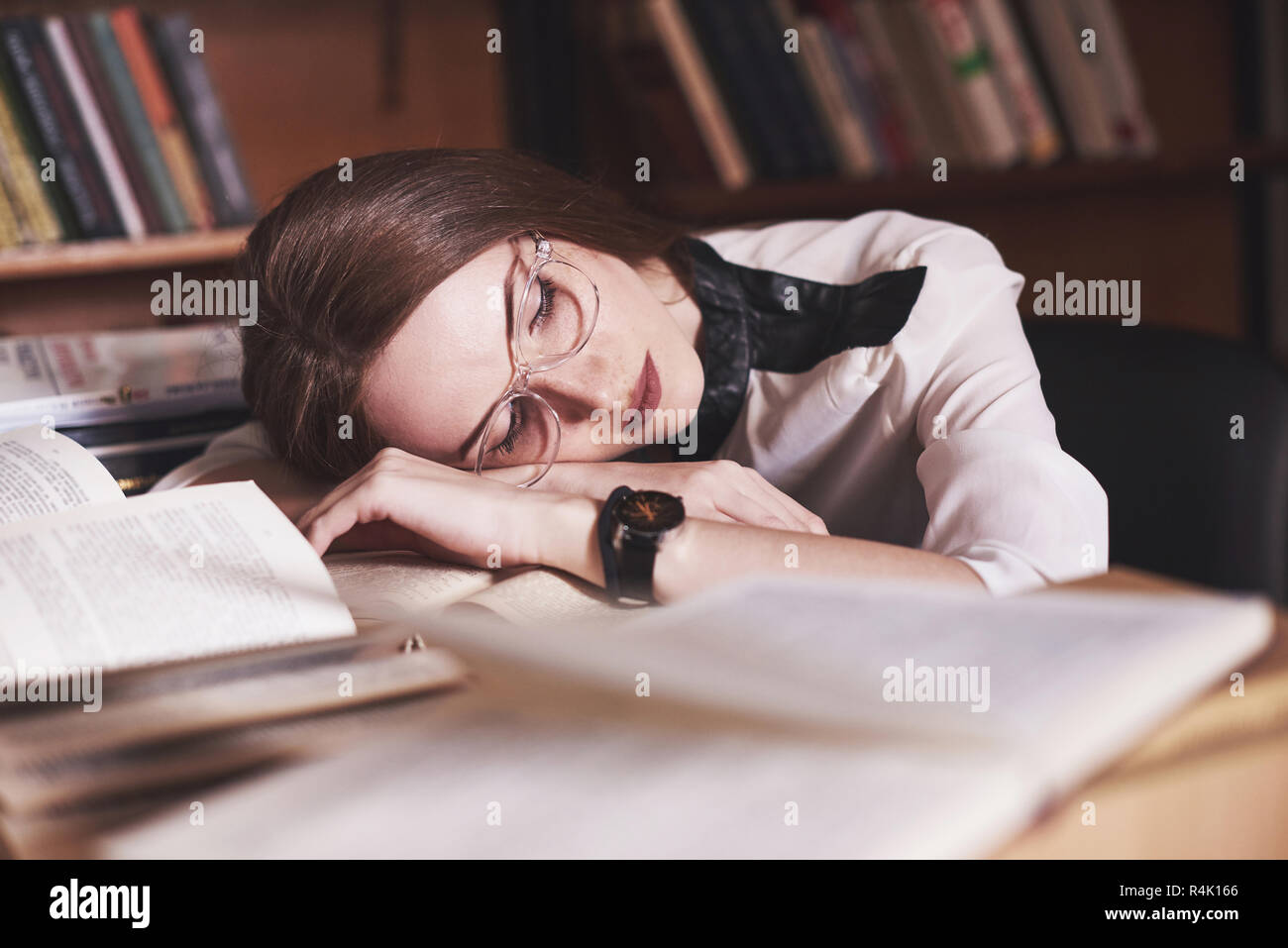 A young girl student is tired in the reading room of the old library ...