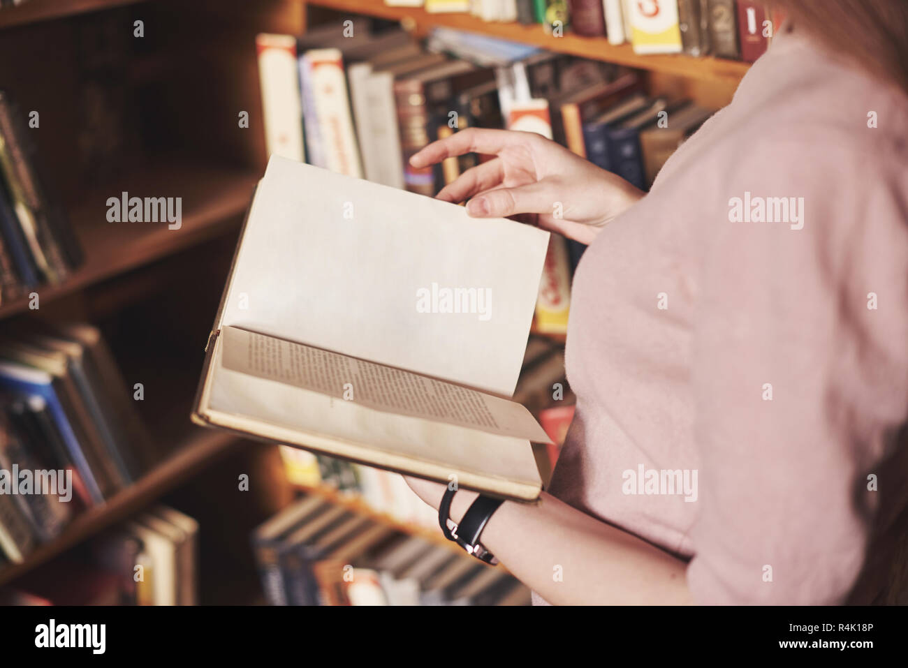 Young attractive student librarian reading a book between library ...