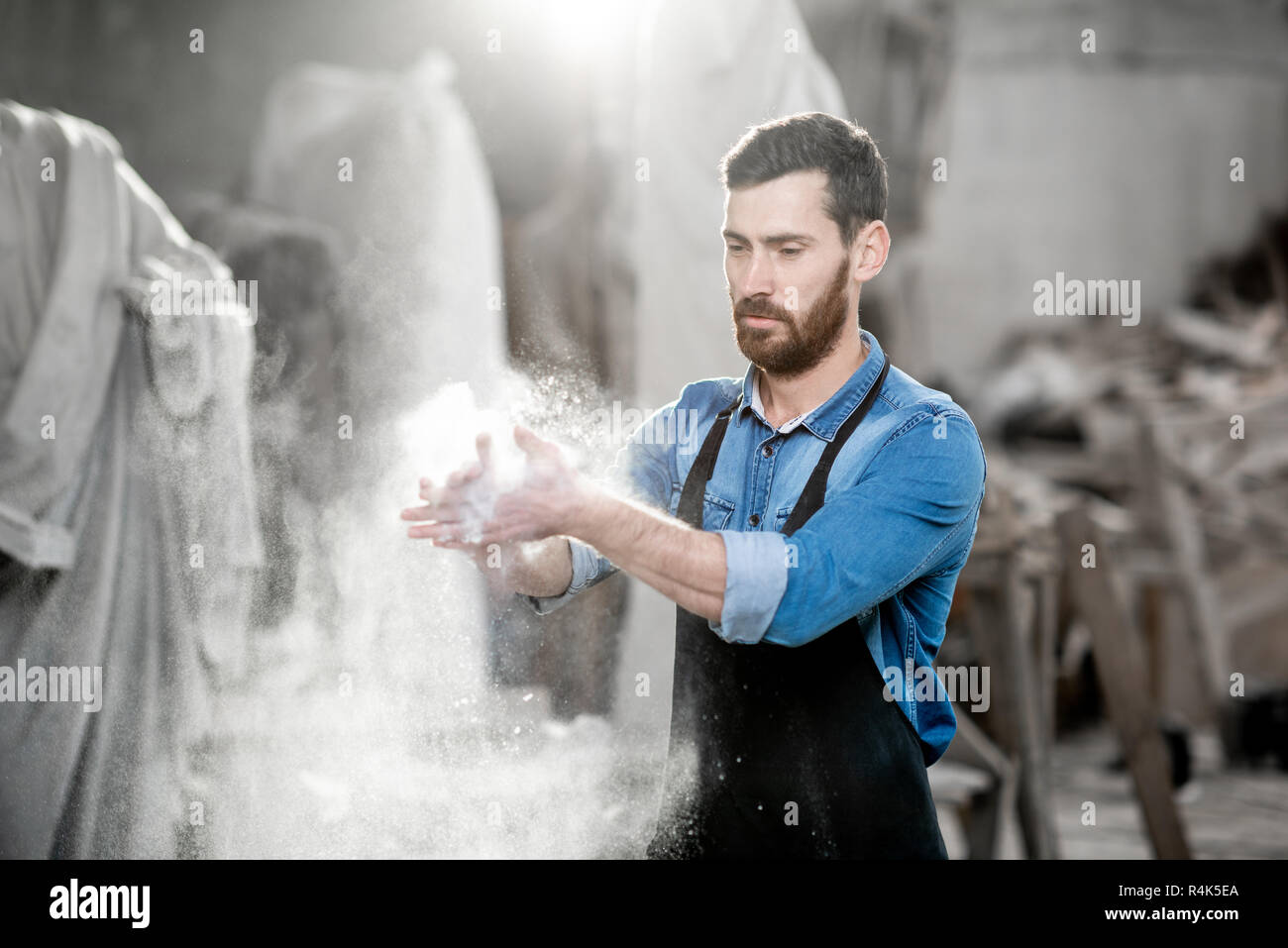 Sculptor clapping hands shaking the dust after the work in the studio ...