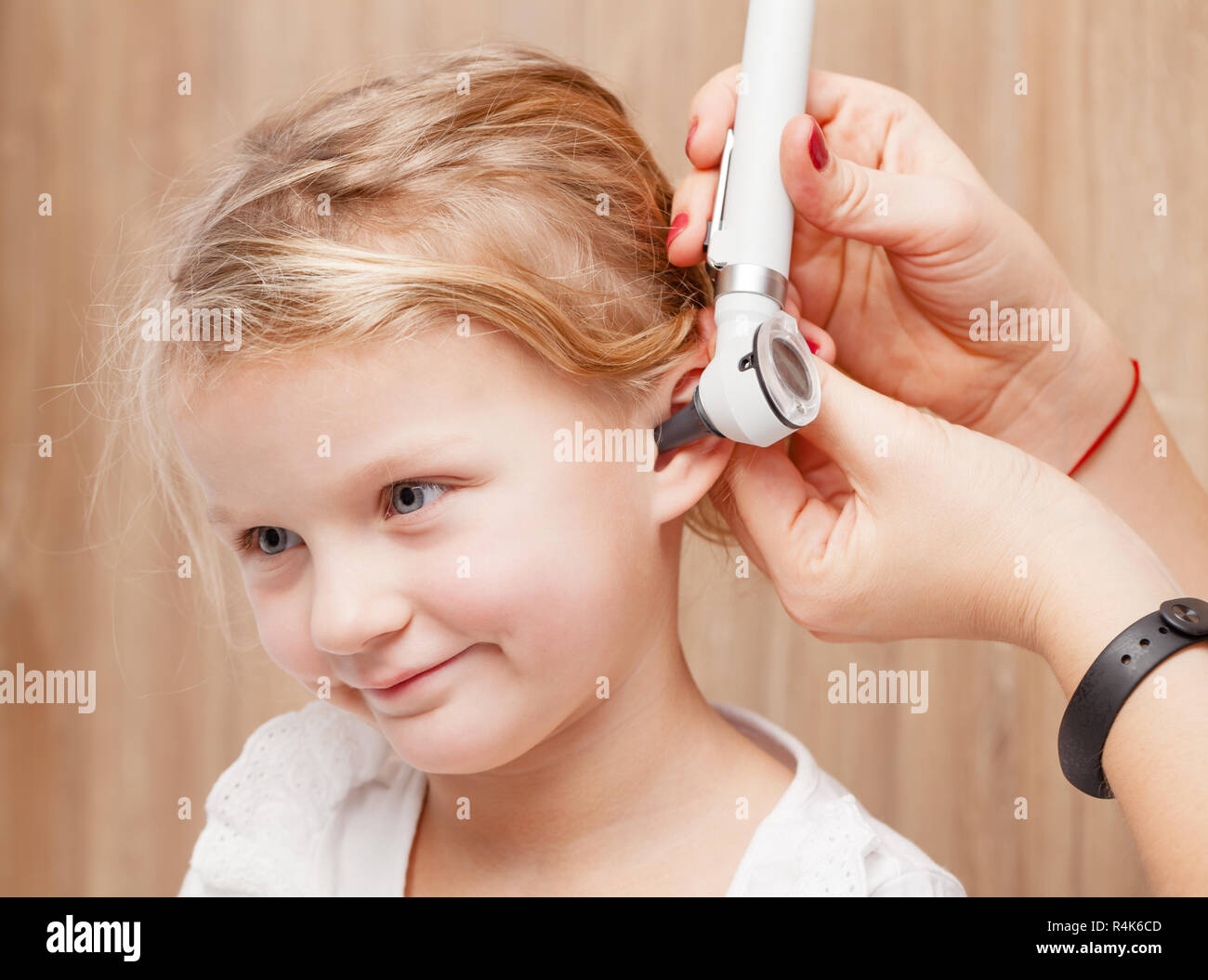 Female pediatrician examines little girl's ear. Doctor using a otoscope ...