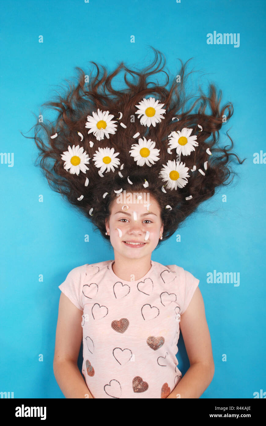 Portrait of a young girl with daisies in their hair lying on the floor ...