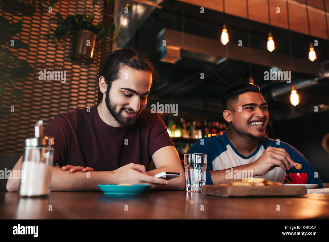 Happy arabian young men hanging in loft cafe. Two mixed race friends ...