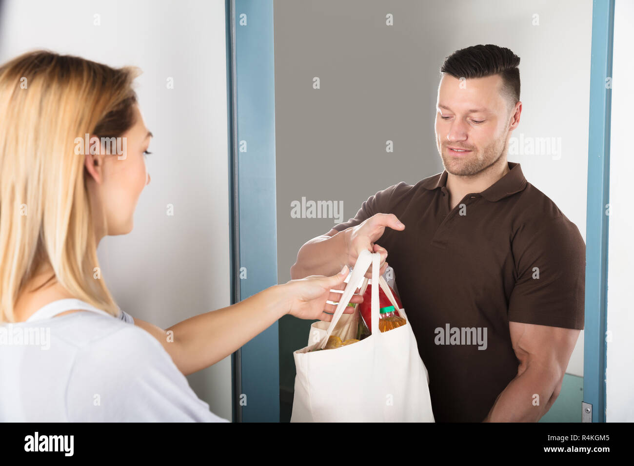 Man Giving Bag Of Grocery To Woman Stock Photo - Alamy