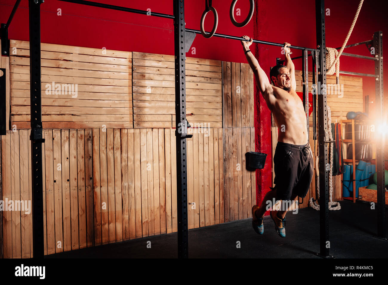 Athletic young man doing pull ups exercises without t-shirt in a ...