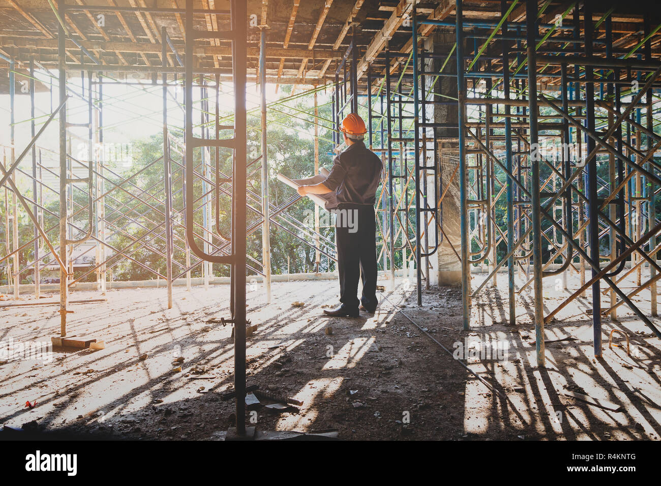 Engineer with blueprint in building construction site Stock Photo - Alamy