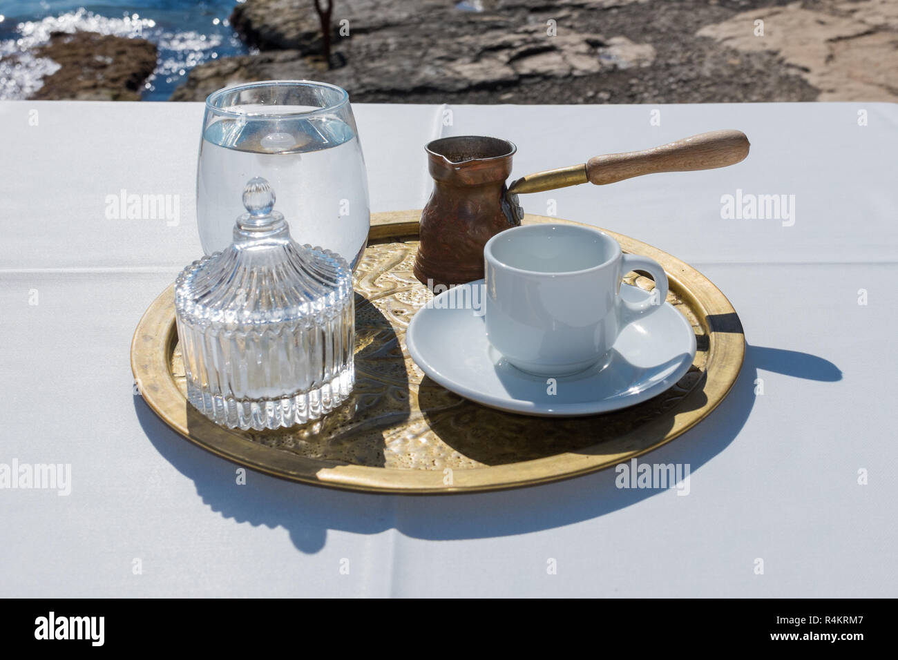Greek coffee kettle with cup and saucer and glass of water on brass ...