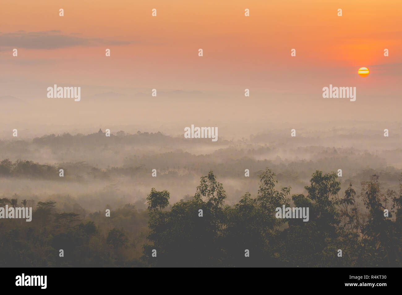 Colorful sunrise over Merapi volcano and Borobudur temple in misty ...