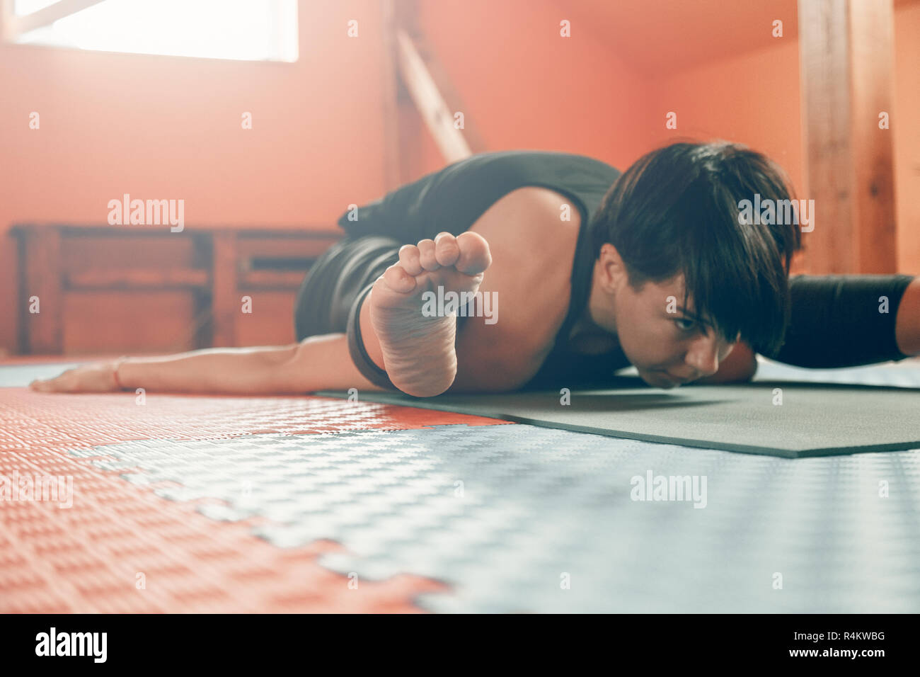 Female doing advanced kurmasana tortoise pose on mat indoors while ...